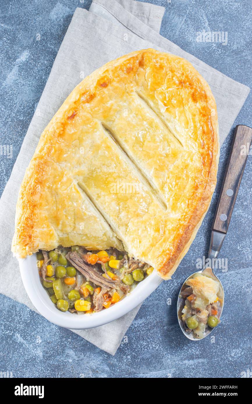 Beef pot pie or deep dish pie in in baking dish, crust broken open to ...