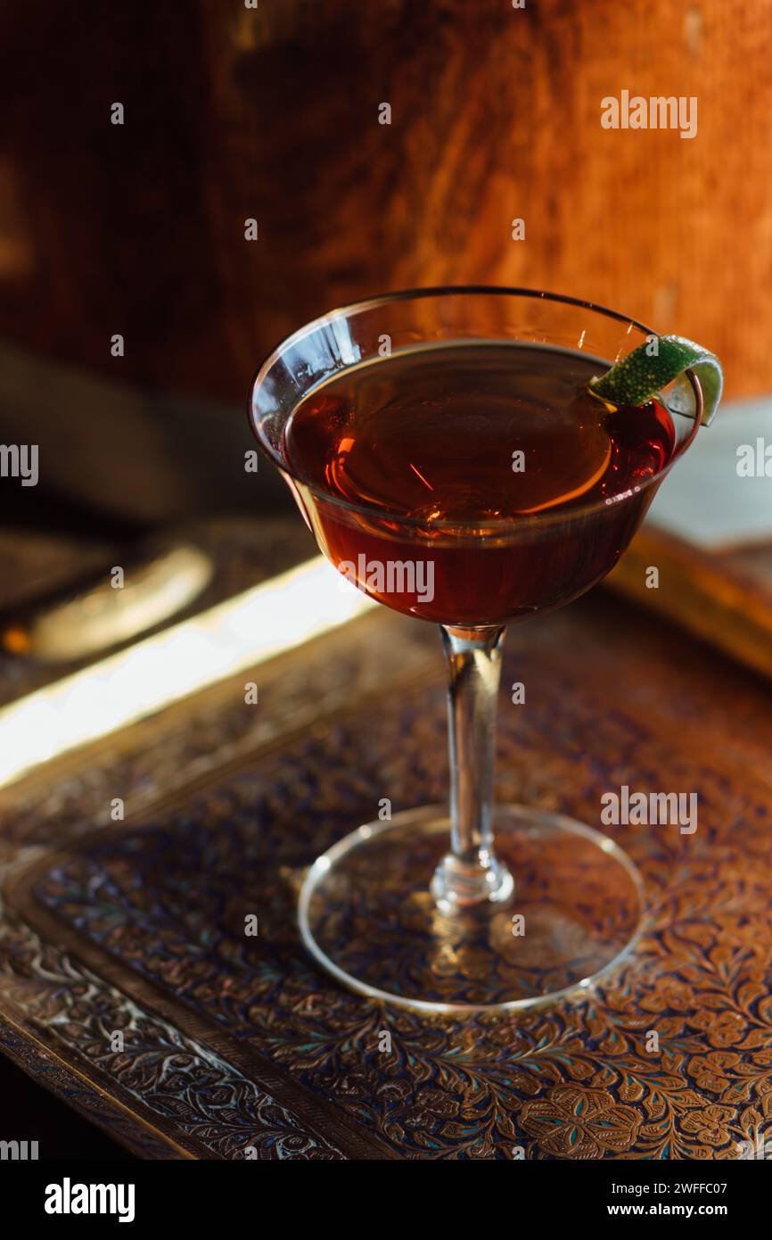 elegant whiskey based cocktail with lime zest twist on ornate brass ...