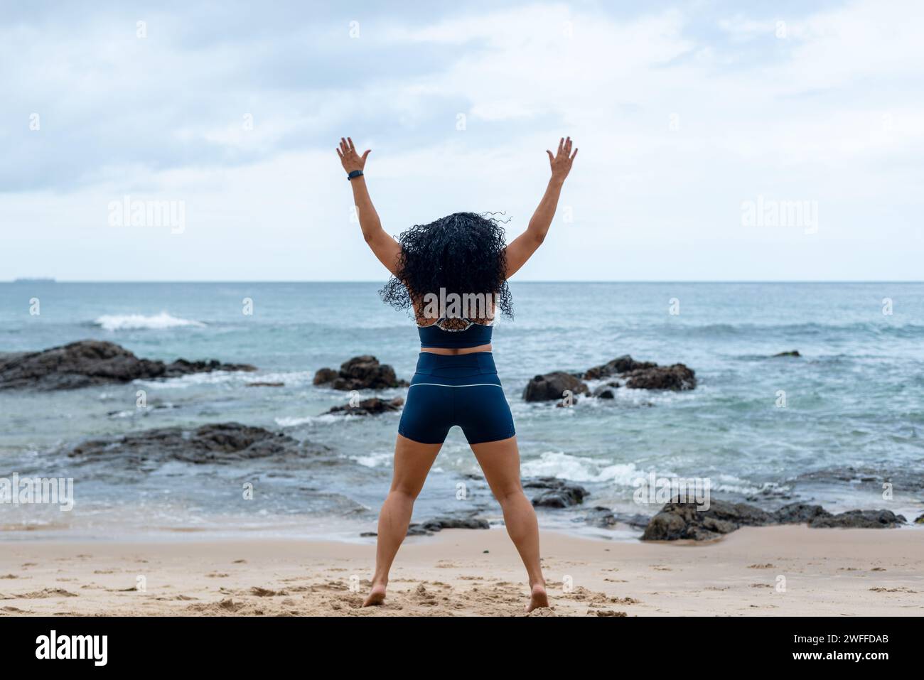 Fitness woman, athlete, doing jumping jacks on the beach sand. Healthy ...