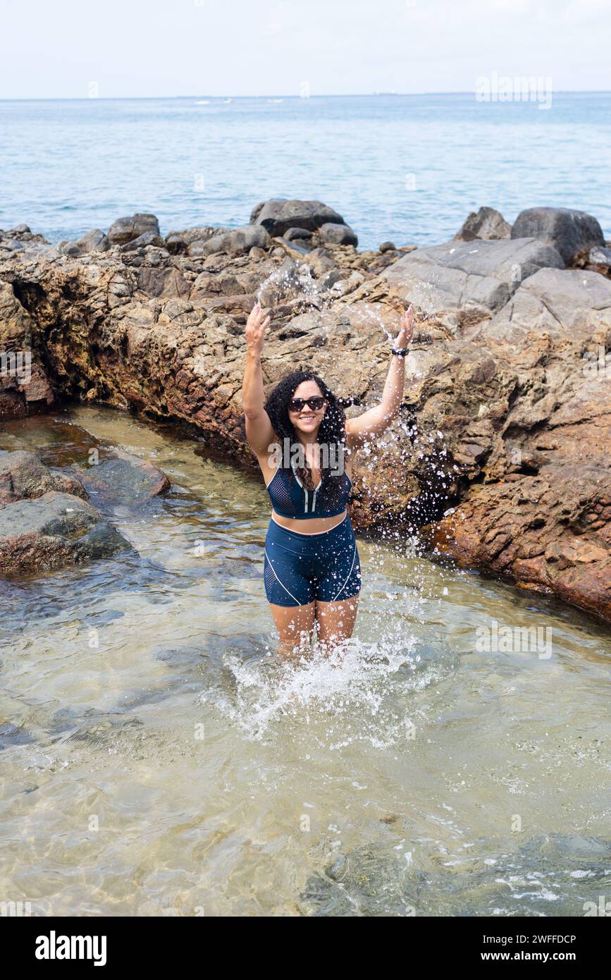 Beautiful woman in a puddle on the beach, throwing water into the air ...