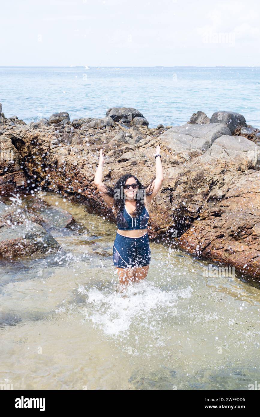 Beautiful woman in a puddle on the beach, throwing water into the air ...