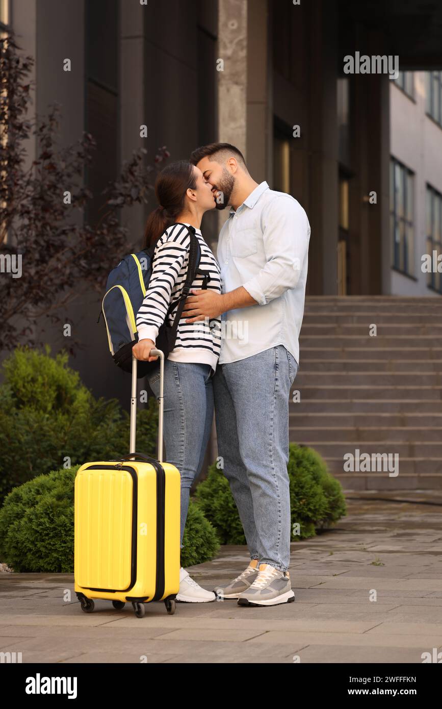 Long-distance relationship. Young woman with luggage kissing her ...