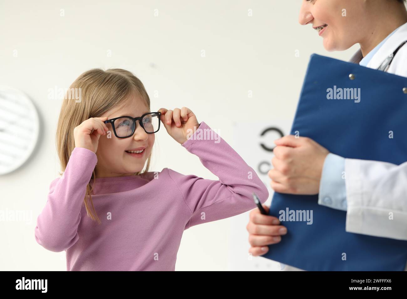 Vision testing. Little girl trying glasses at ophthalmologist office ...