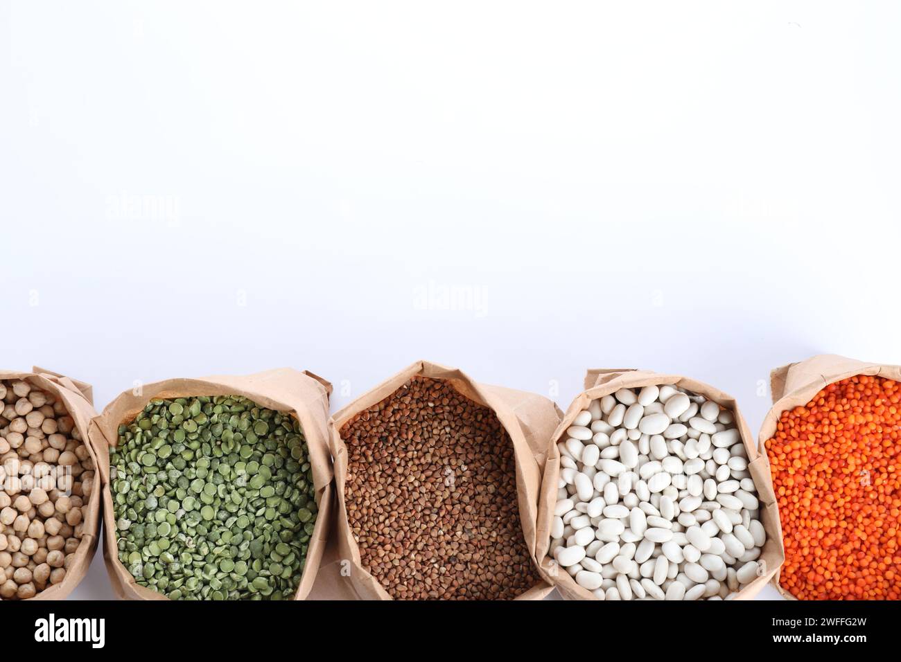 Different types of legumes and cereals in paper bags on white ...