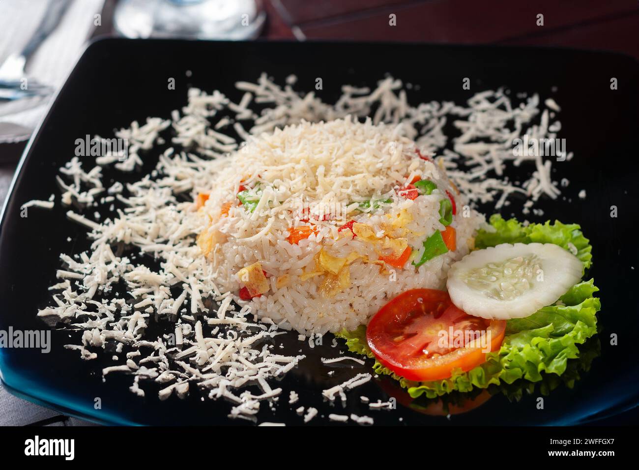 Nasi Goreng Keju or cheese fried rice in black plate with vegetable as ...