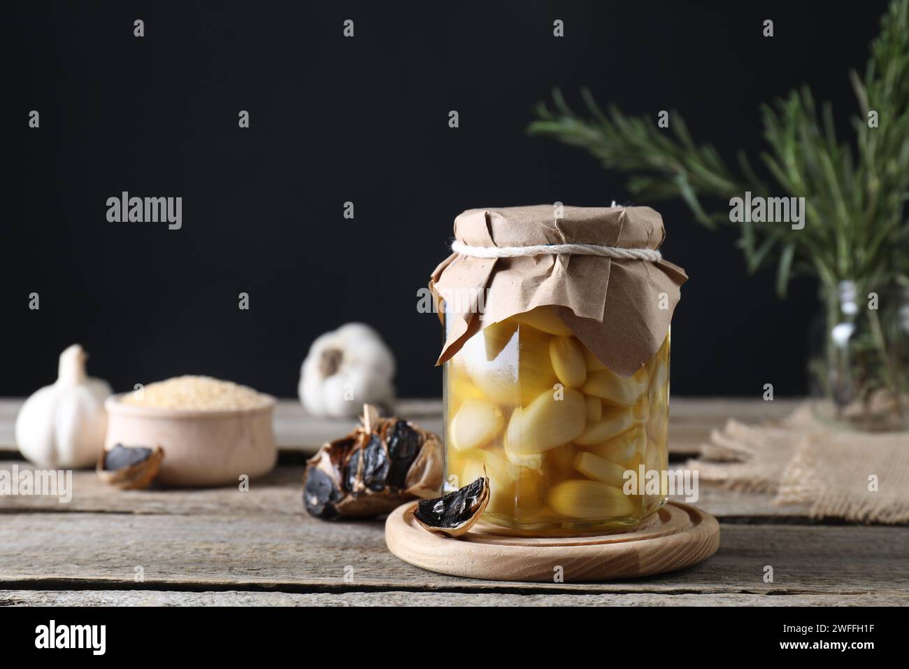 Garlic with honey in glass jar and fermented black garlic on wooden ...