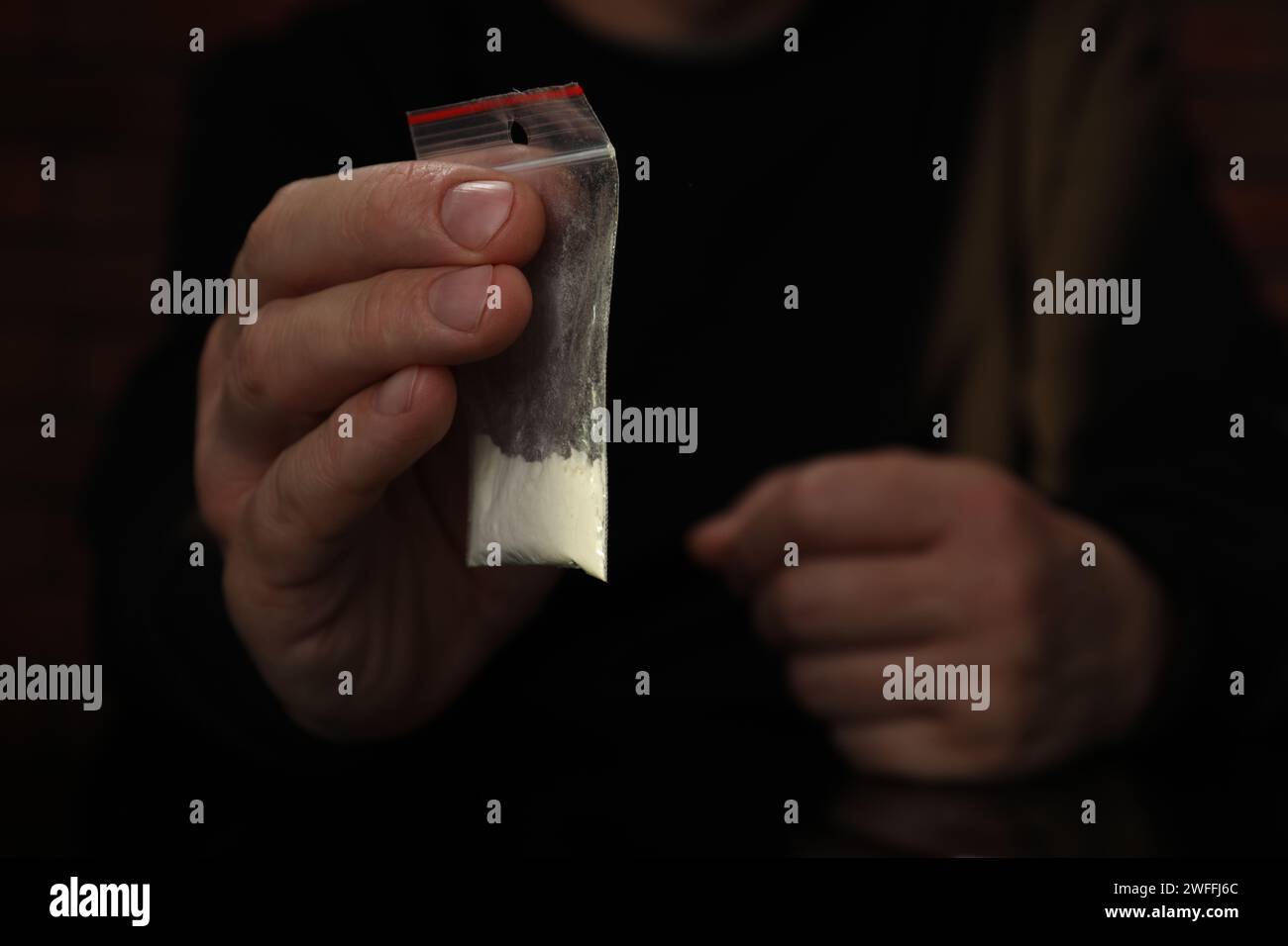 Drug addiction. Man with plastic bag of cocaine on dark background ...