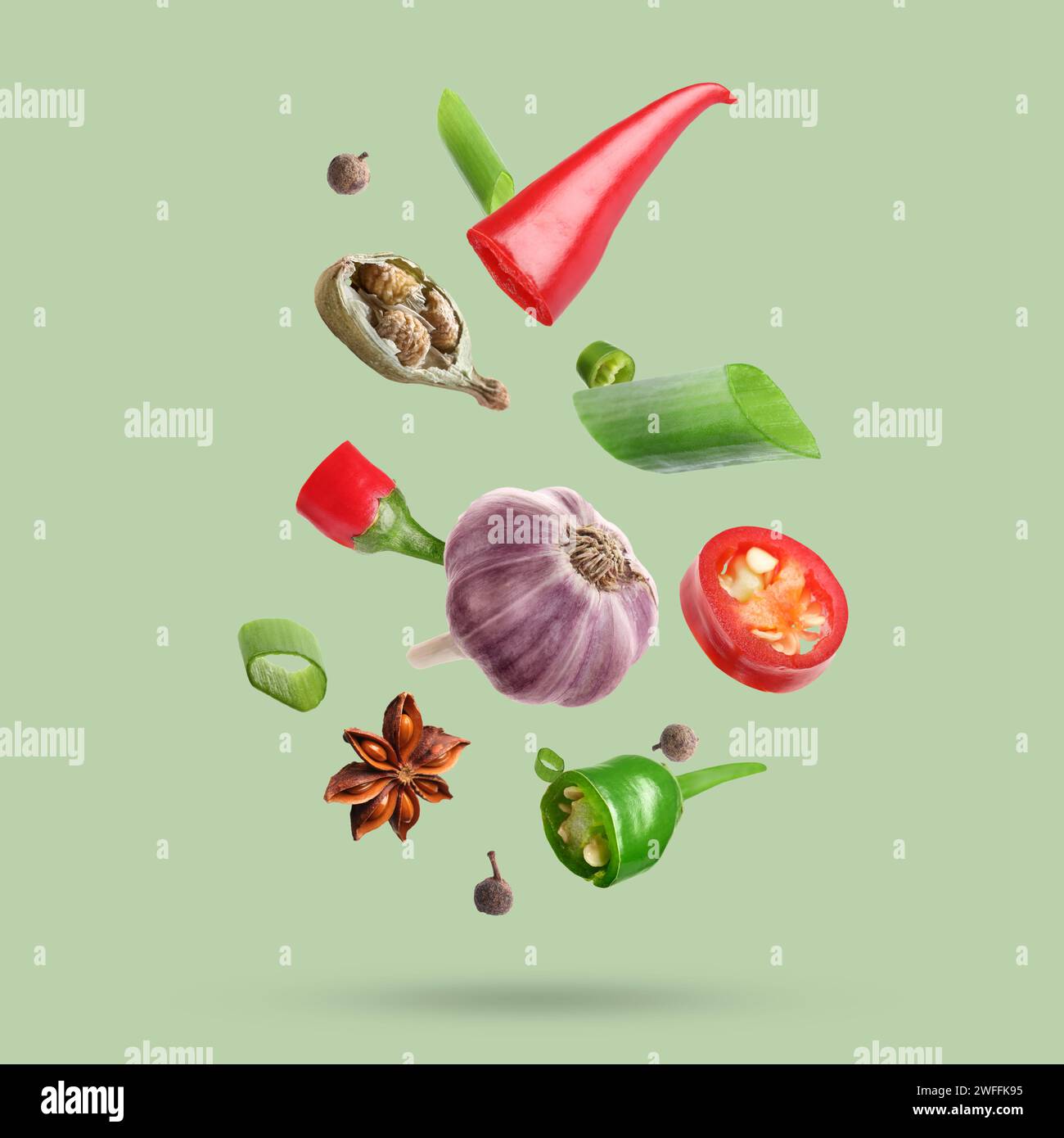 Different spices falling on light green background Stock Photo - Alamy