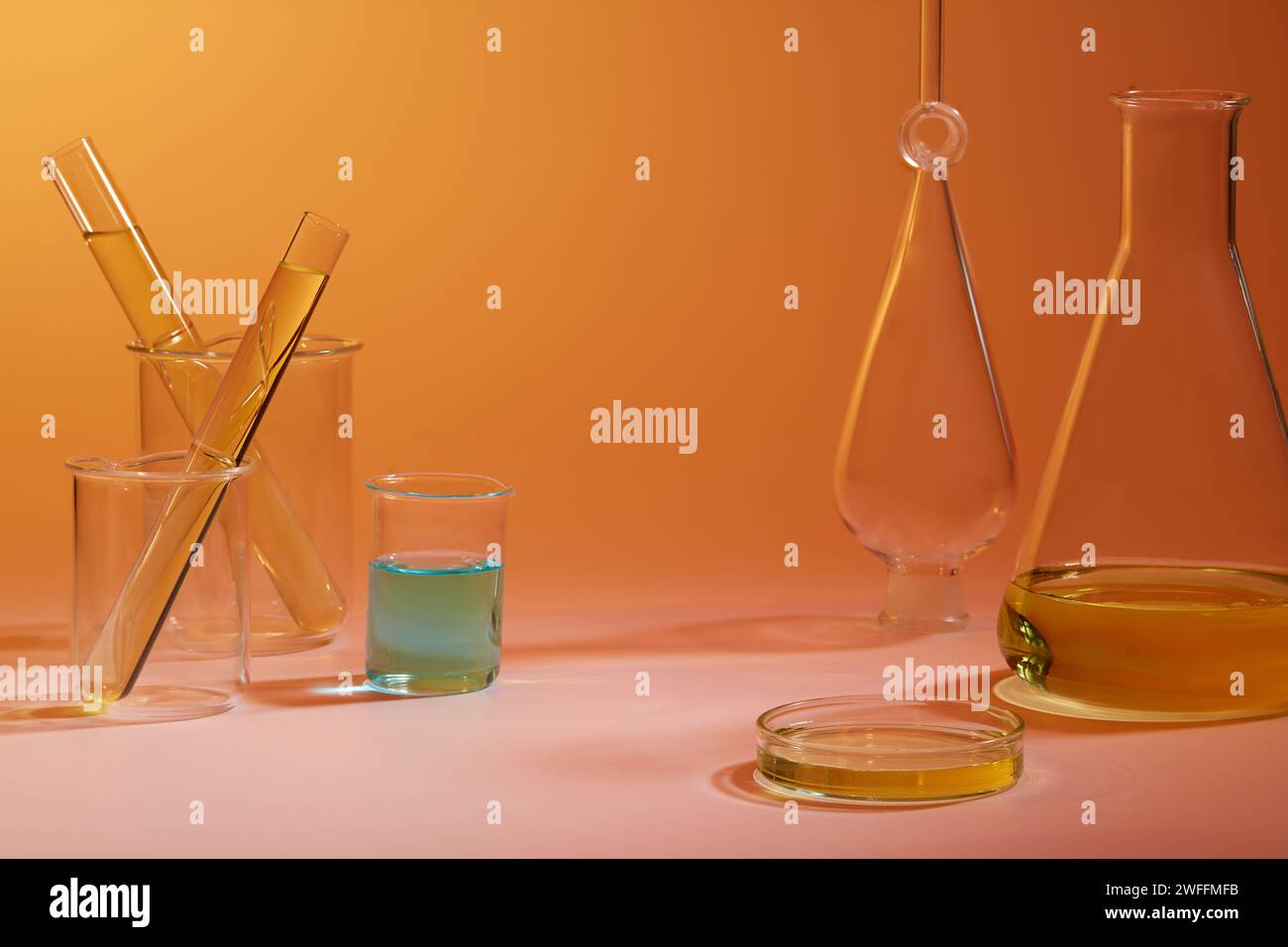 Orange background with many laboratory glassware filled yellow and blue ...