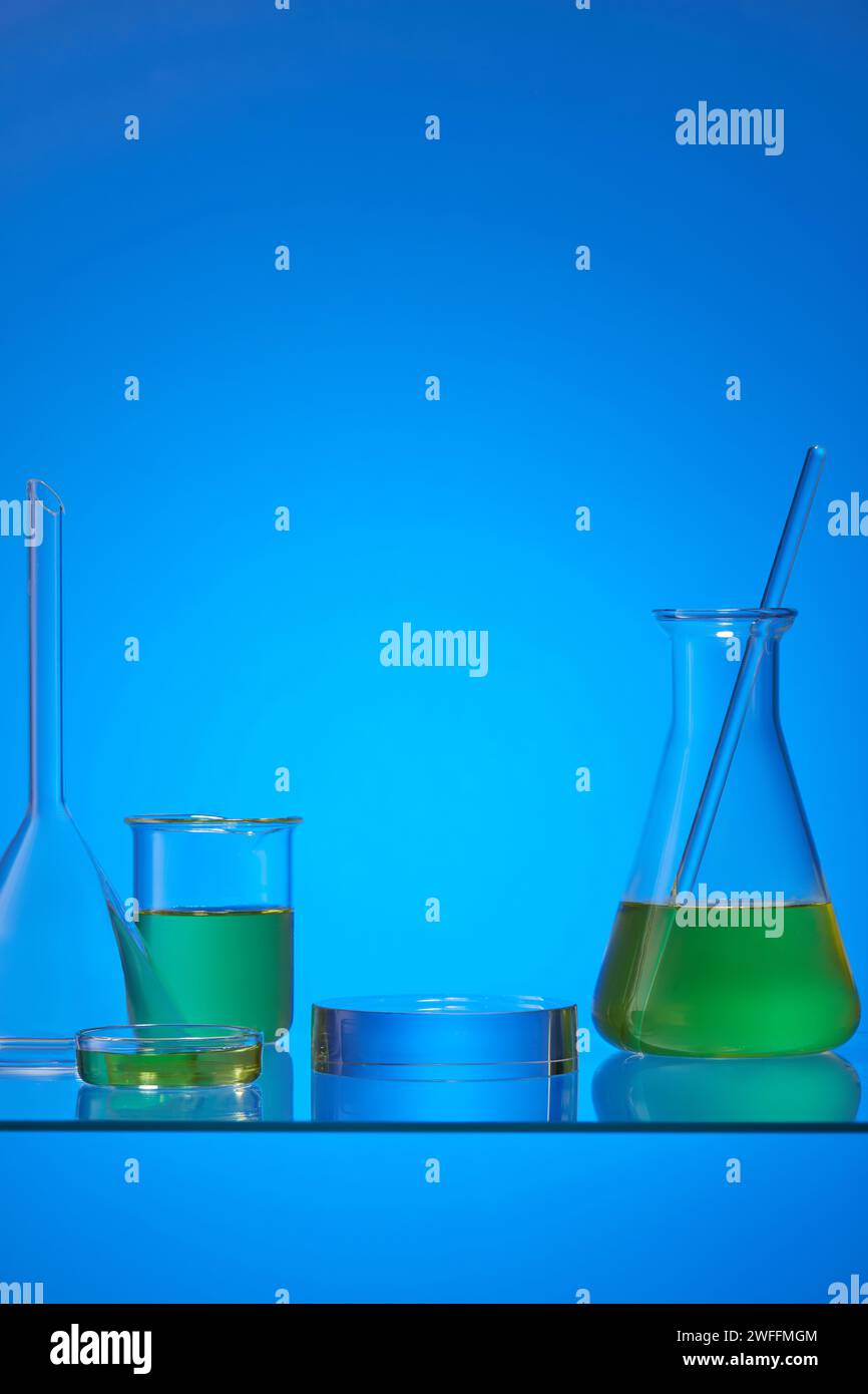 An erlenmeyer flask, petri dish and beaker filled with yellow fluid on ...