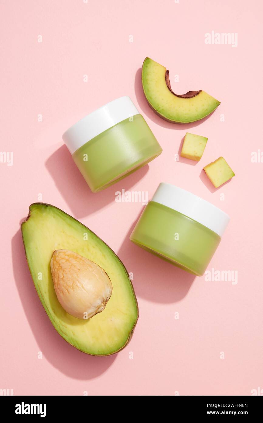 Avocado slices arranged with two unlabeled jars on light pink ...