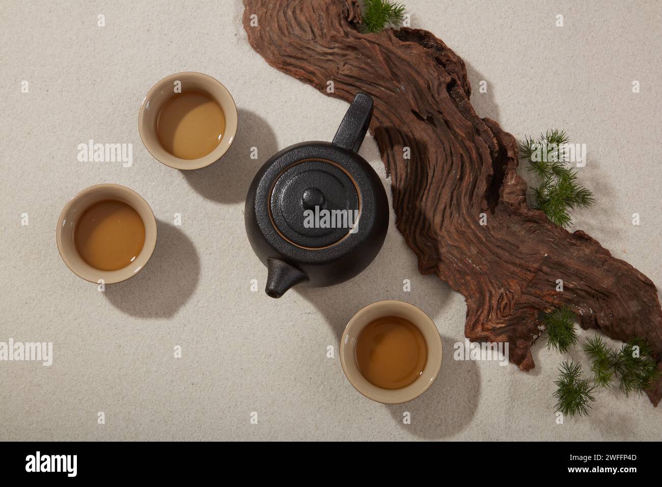 Flat lay of a tea set including an earthen teapot and several tea cups ...