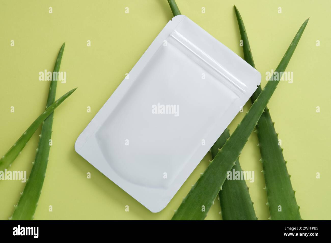 Unlabeled beauty mask sheet with Aloe vera leaves on pastel background ...