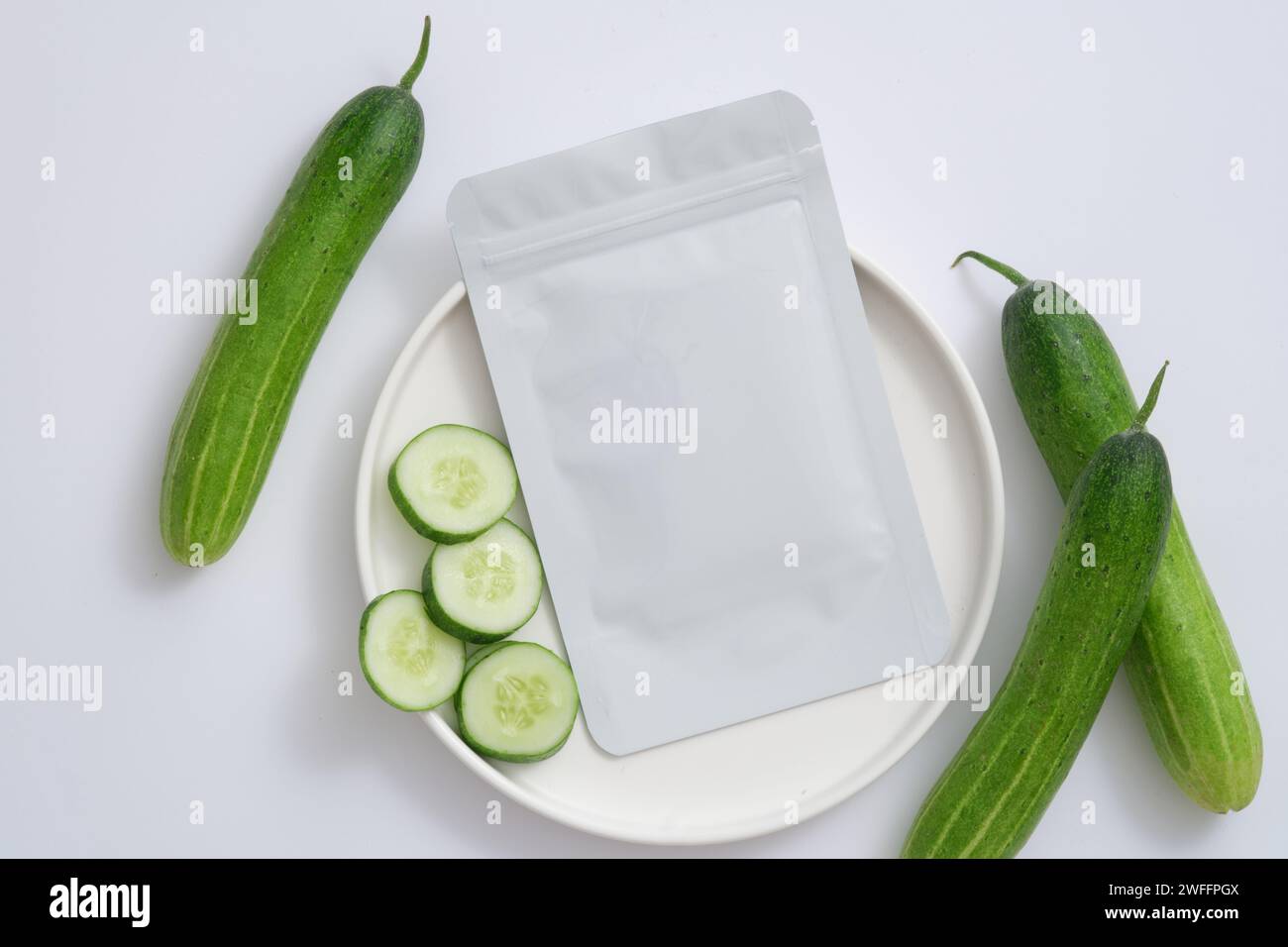 White mask package put on a round dish decorated with Cucumber slices ...