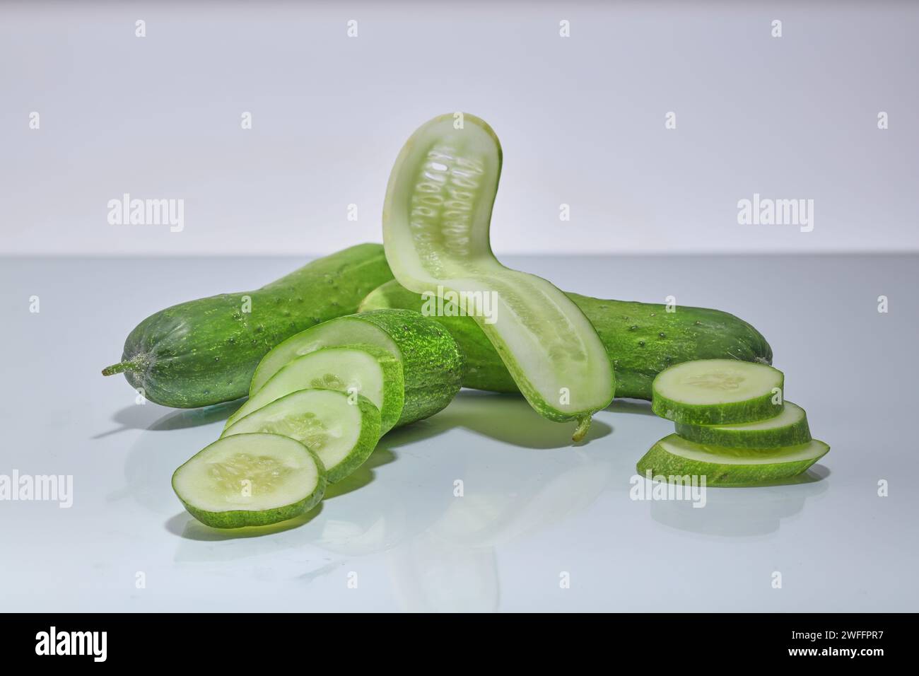 Cucumber cut in slices are decorated on mirror table with white ...