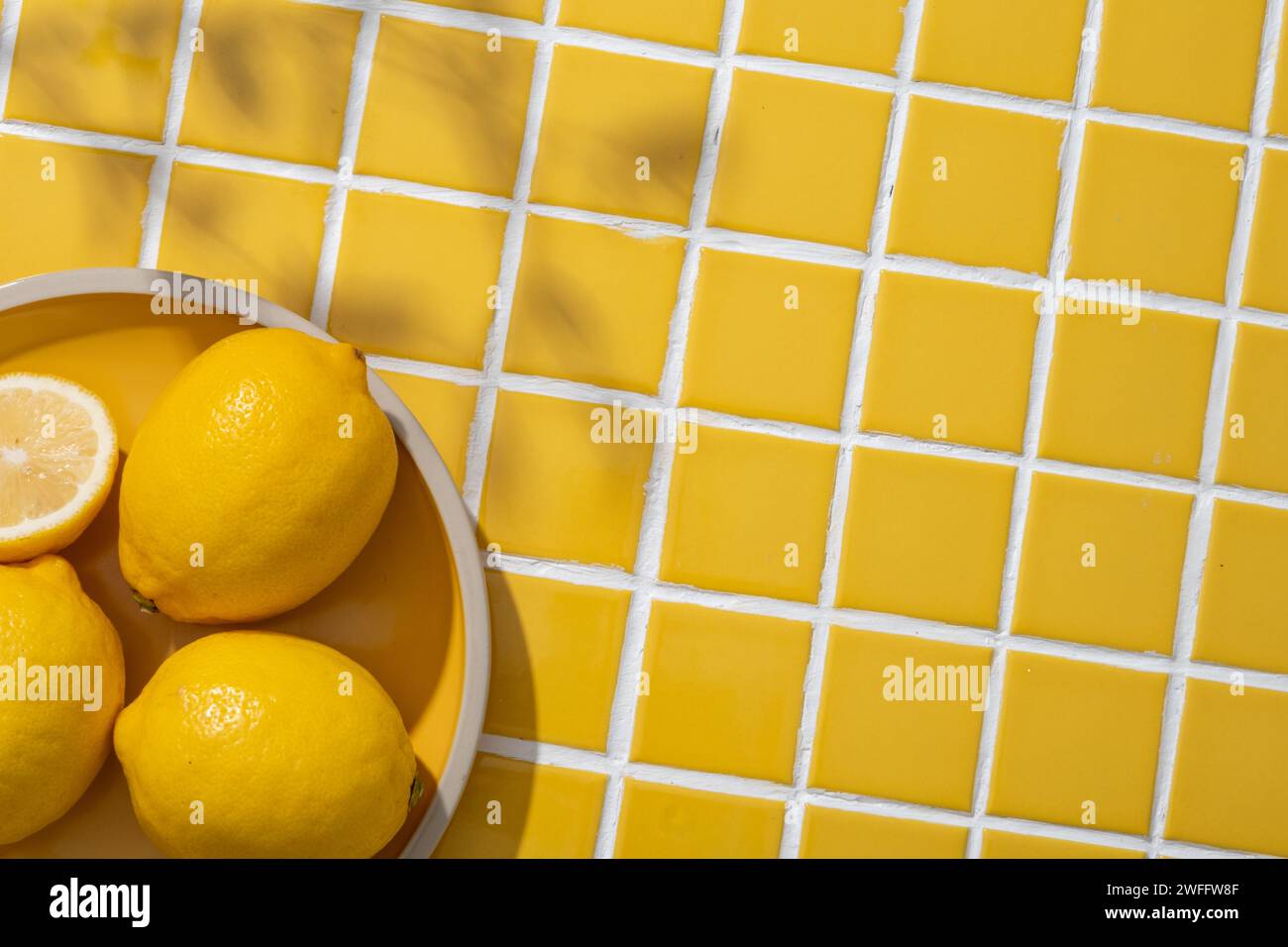 A round-shaped dish of Lemons isolated on yellow mosaic tiles ...