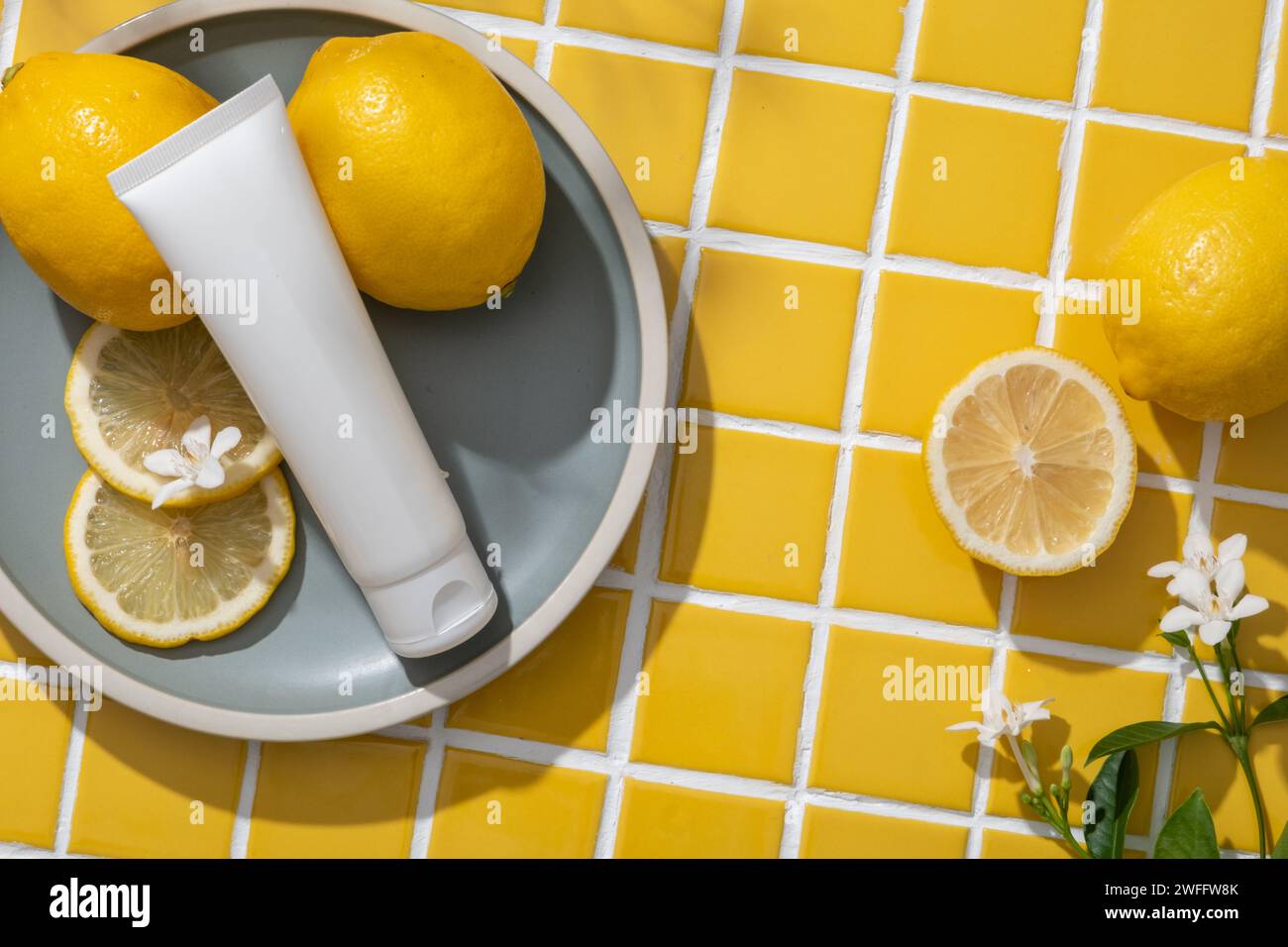 Empty label white tube, Lemon slices and small flower put on a round ...