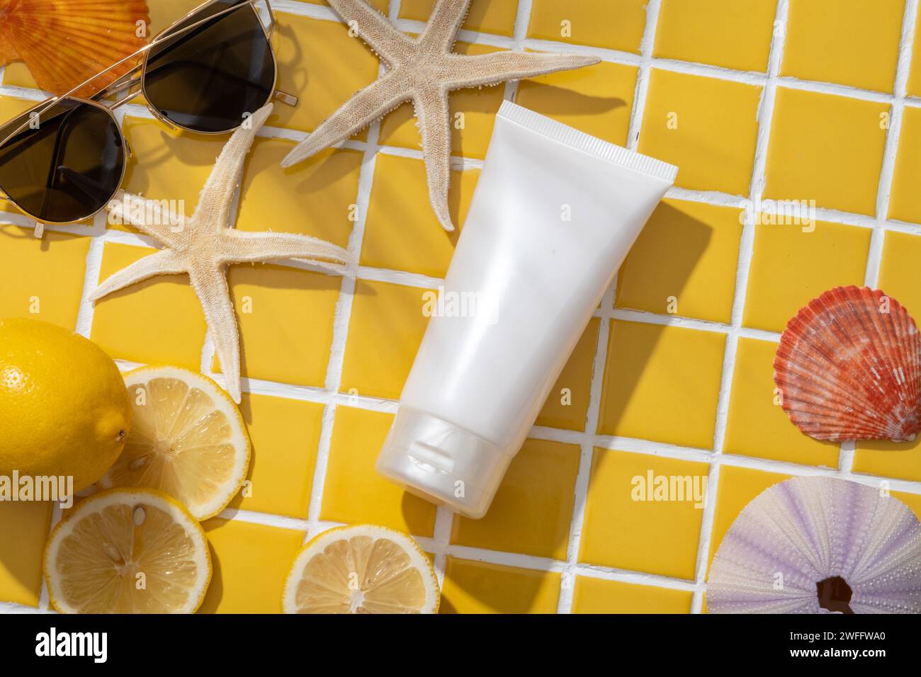 Beauty cosmetic tube arranged with Lemon slices, starfishes, sunglasses ...