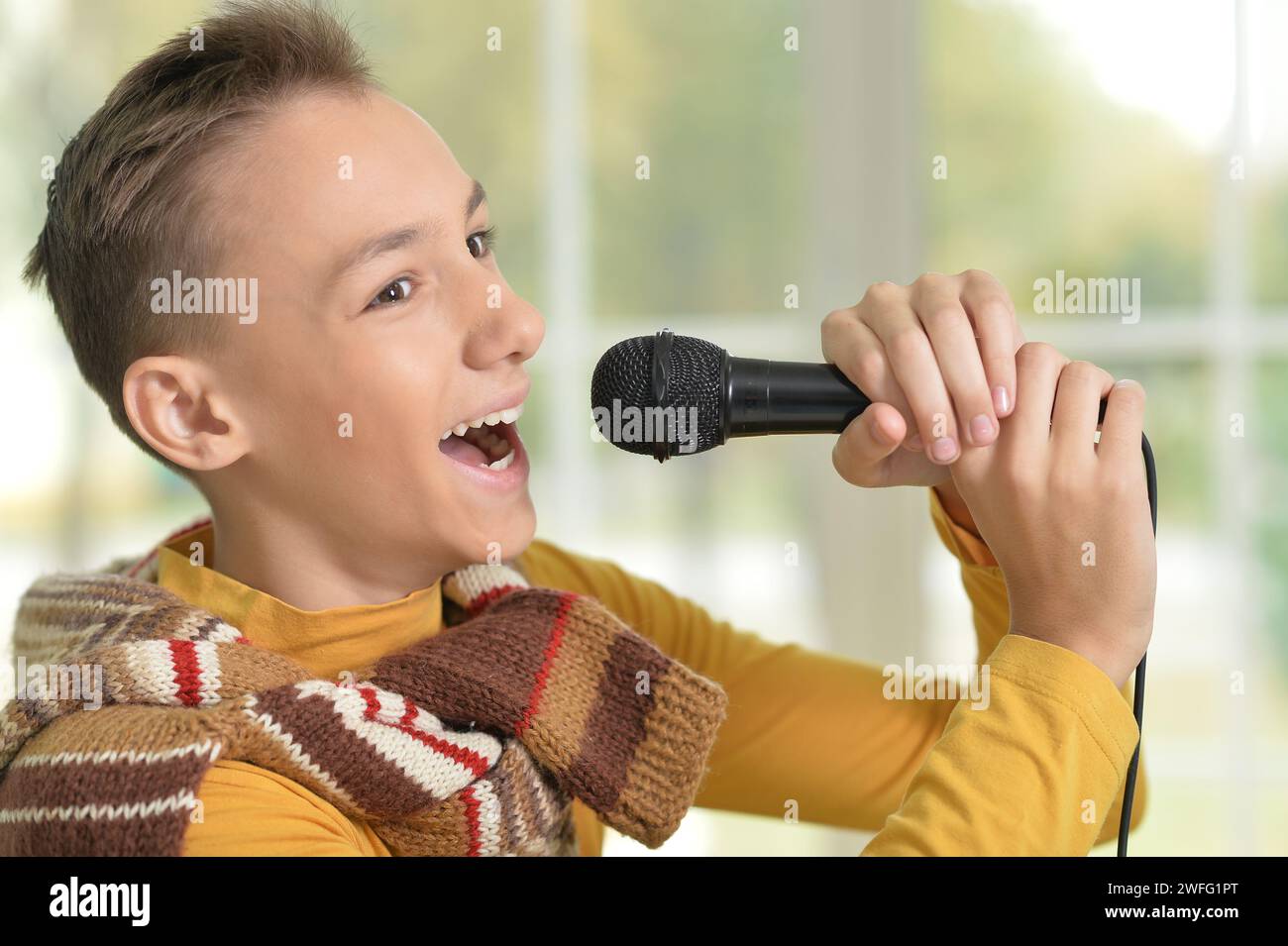 Cute young boy singing into a microphone Stock Photo - Alamy