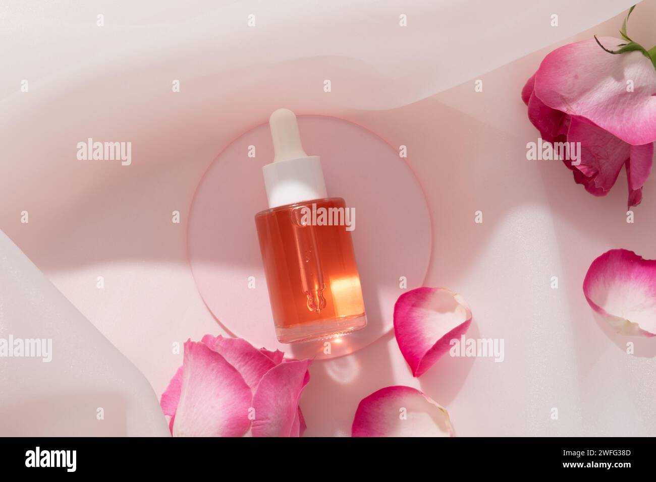 Round acrylic sheet with an empty label dropper bottle of pink liquid ...