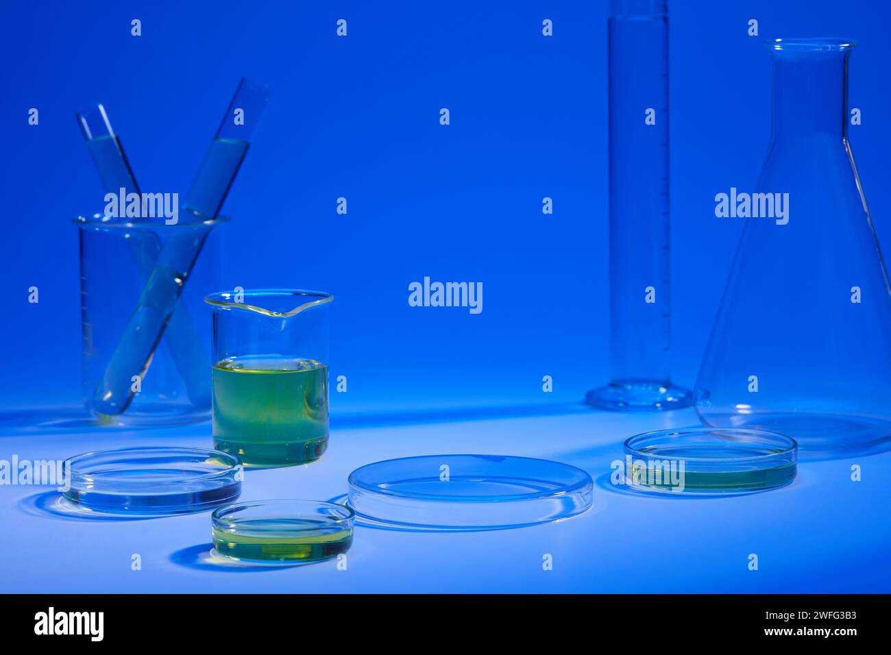 Beaker and petri dish of yellow liquid displayed with other laboratory ...