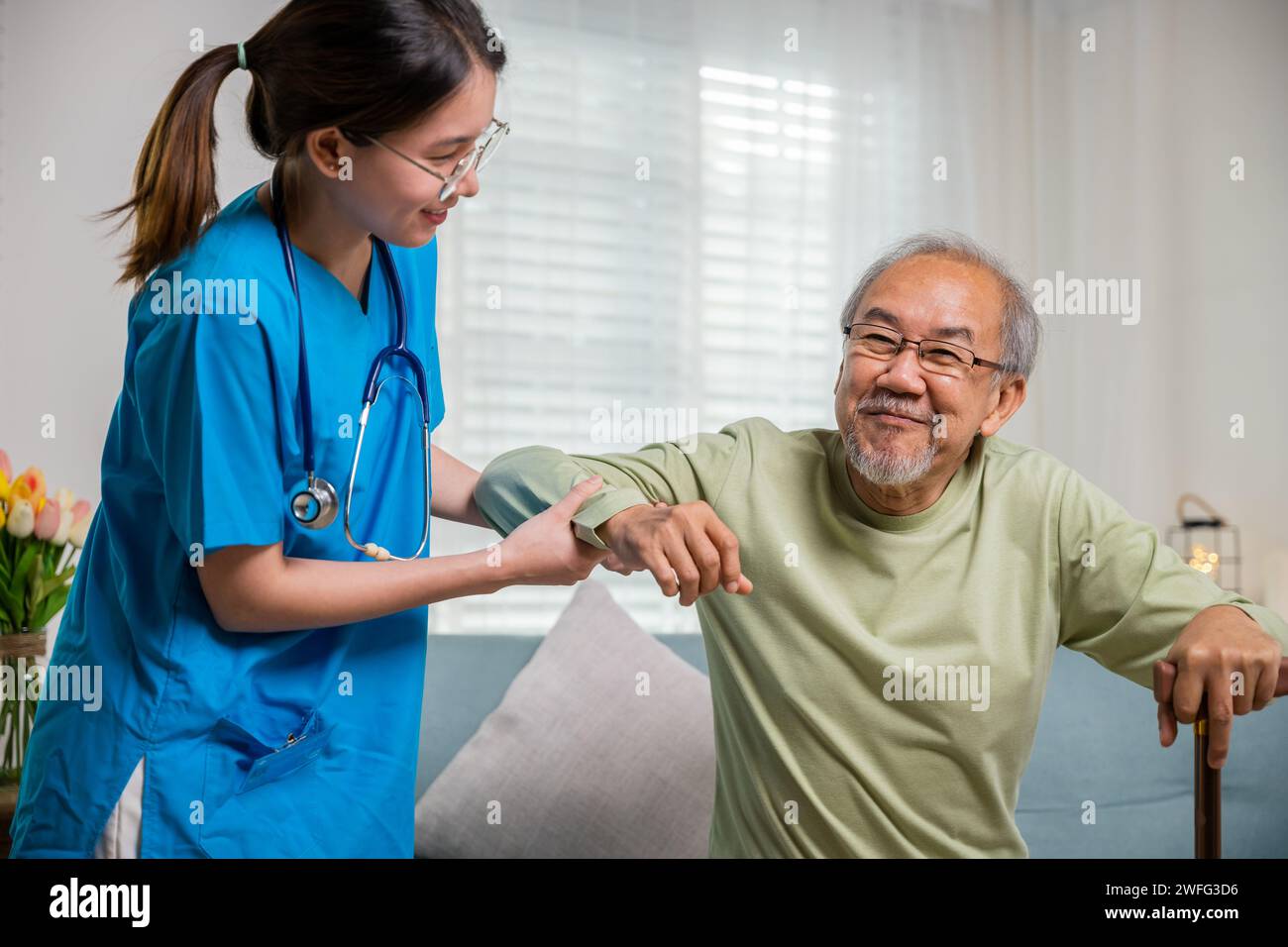 Caring nurse helping supporting senior disabled man to stand up with ...