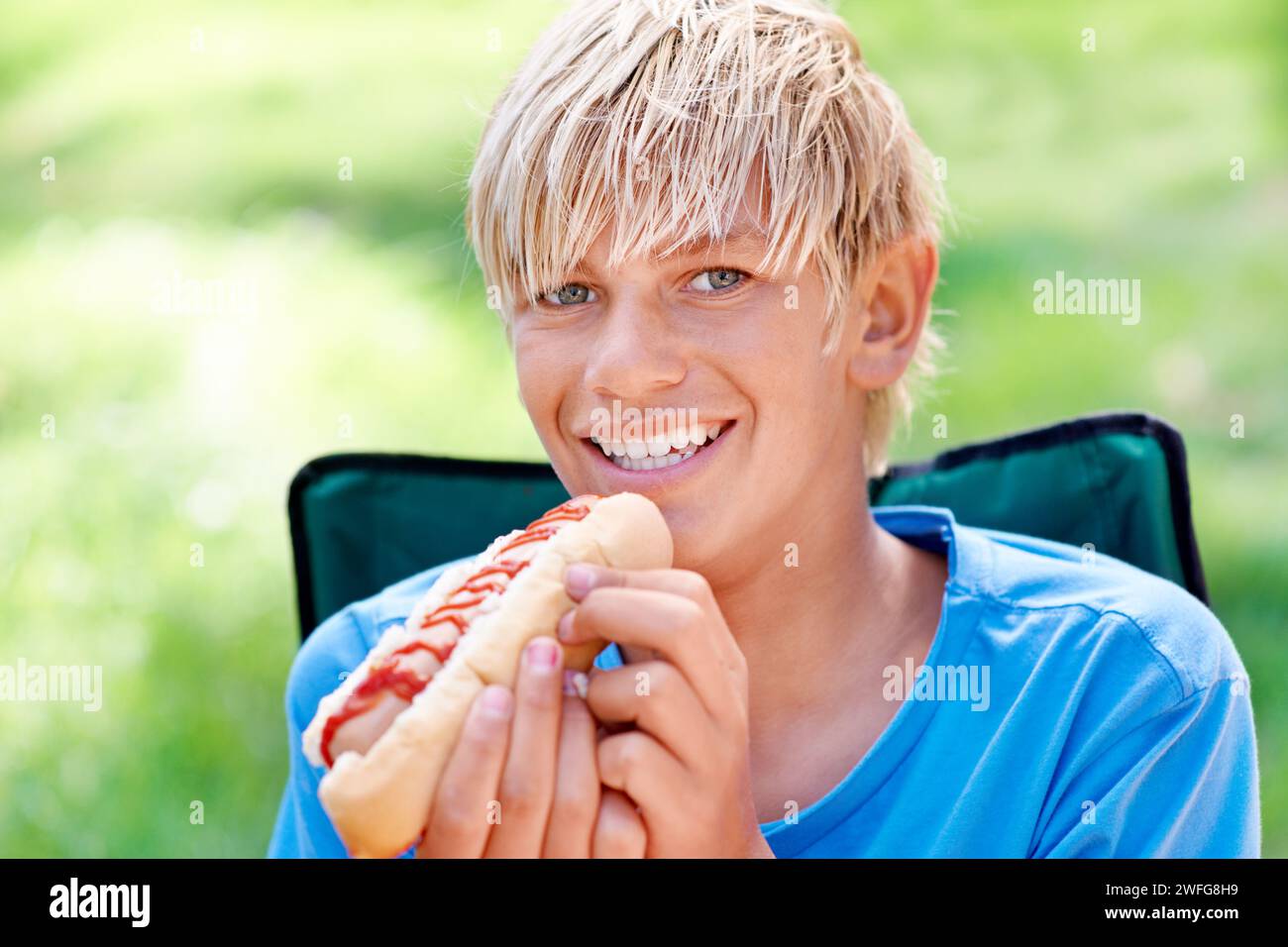 Child, eating and portrait with hotdog outdoor in camping chair and ...