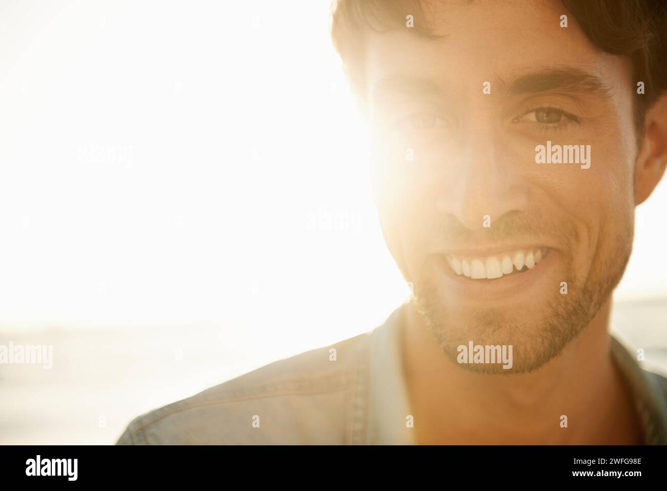 Man, smile portrait and lens flare at the beach on a holiday and summer ...