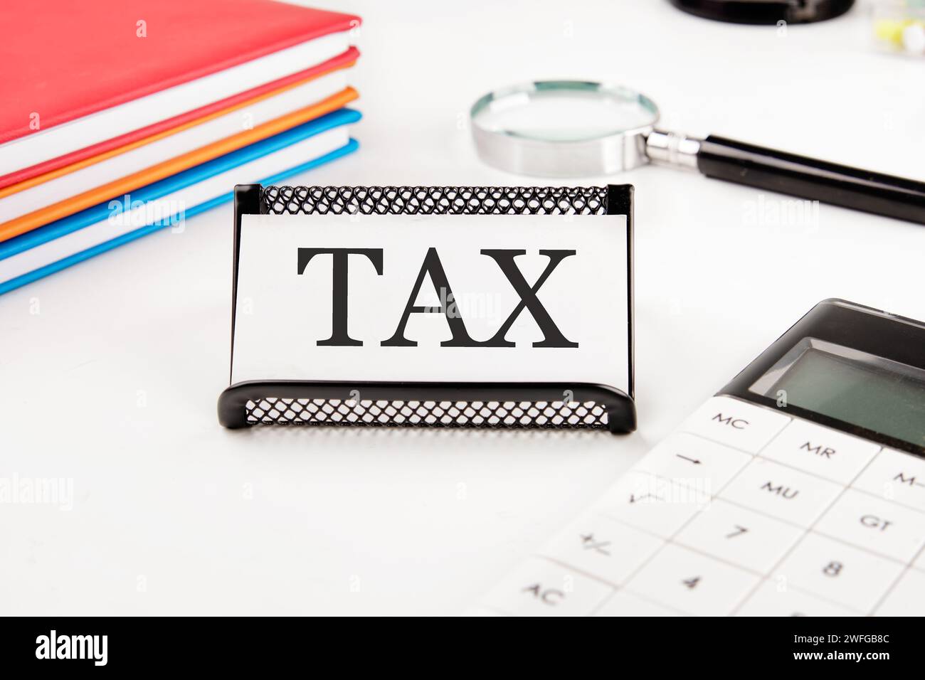 TAX text on a business card next to office supplies on a white ...
