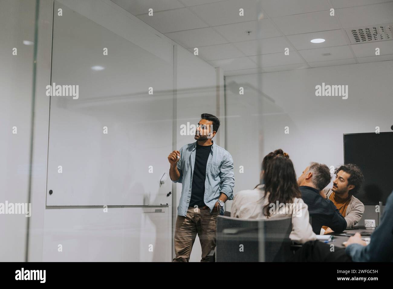 Businessman explaining strategy on whiteboard to colleagues in board ...