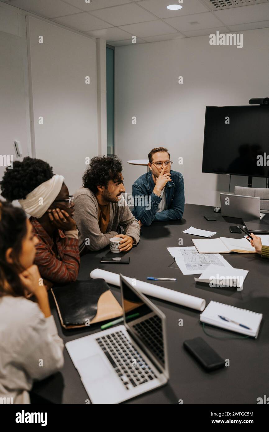 Multiracial colleagues sitting at conference table in board room Stock ...