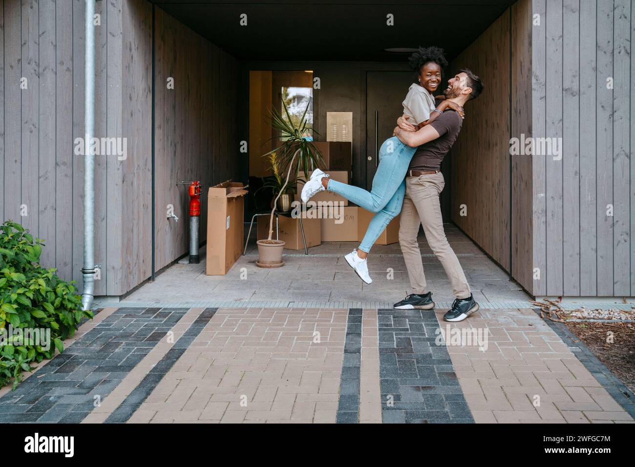 Happy Multiracial Couple Having Fun While Standing At Building Entrance