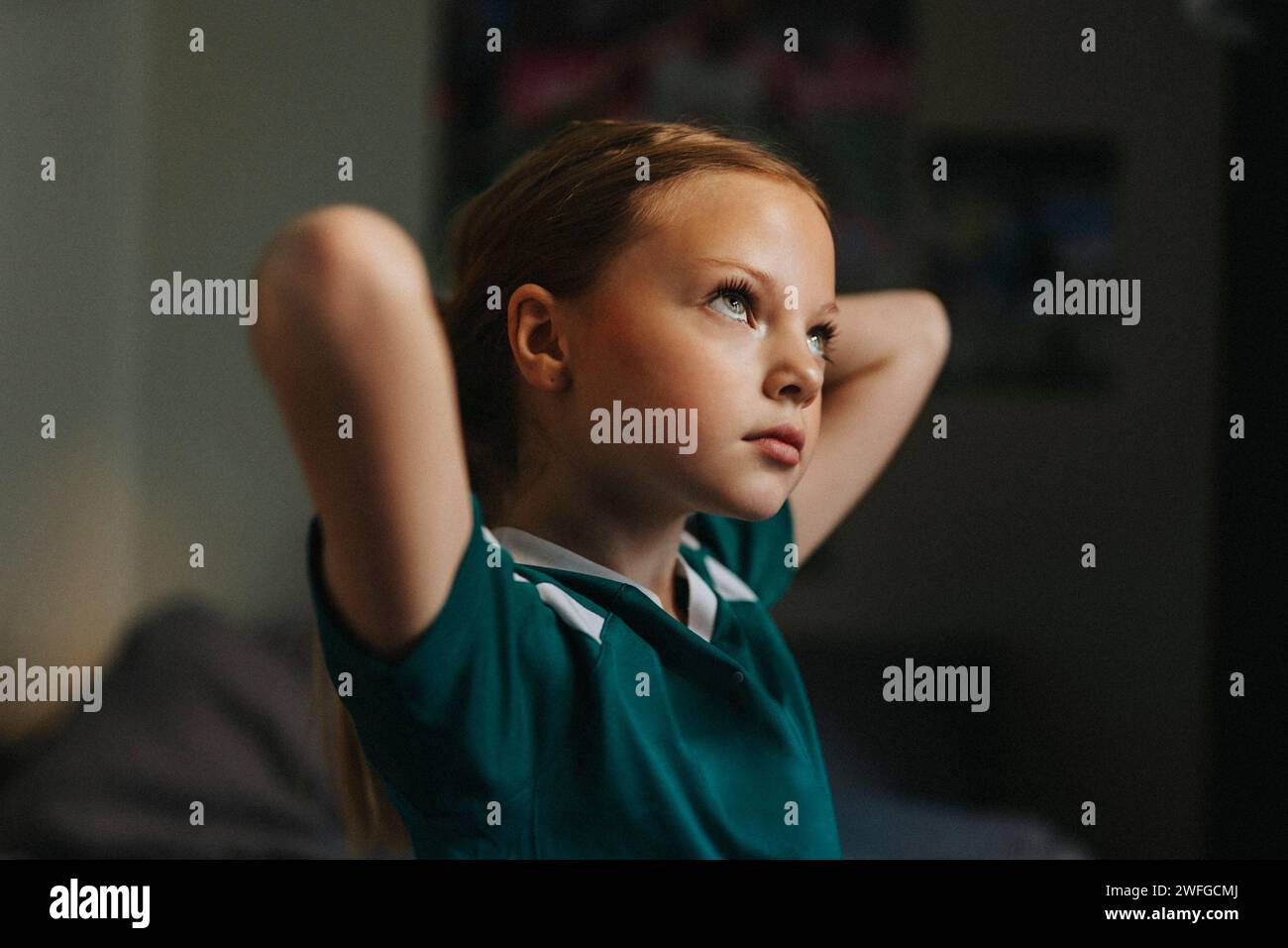 Contemplative girl with hands behind head looking away at home Stock ...