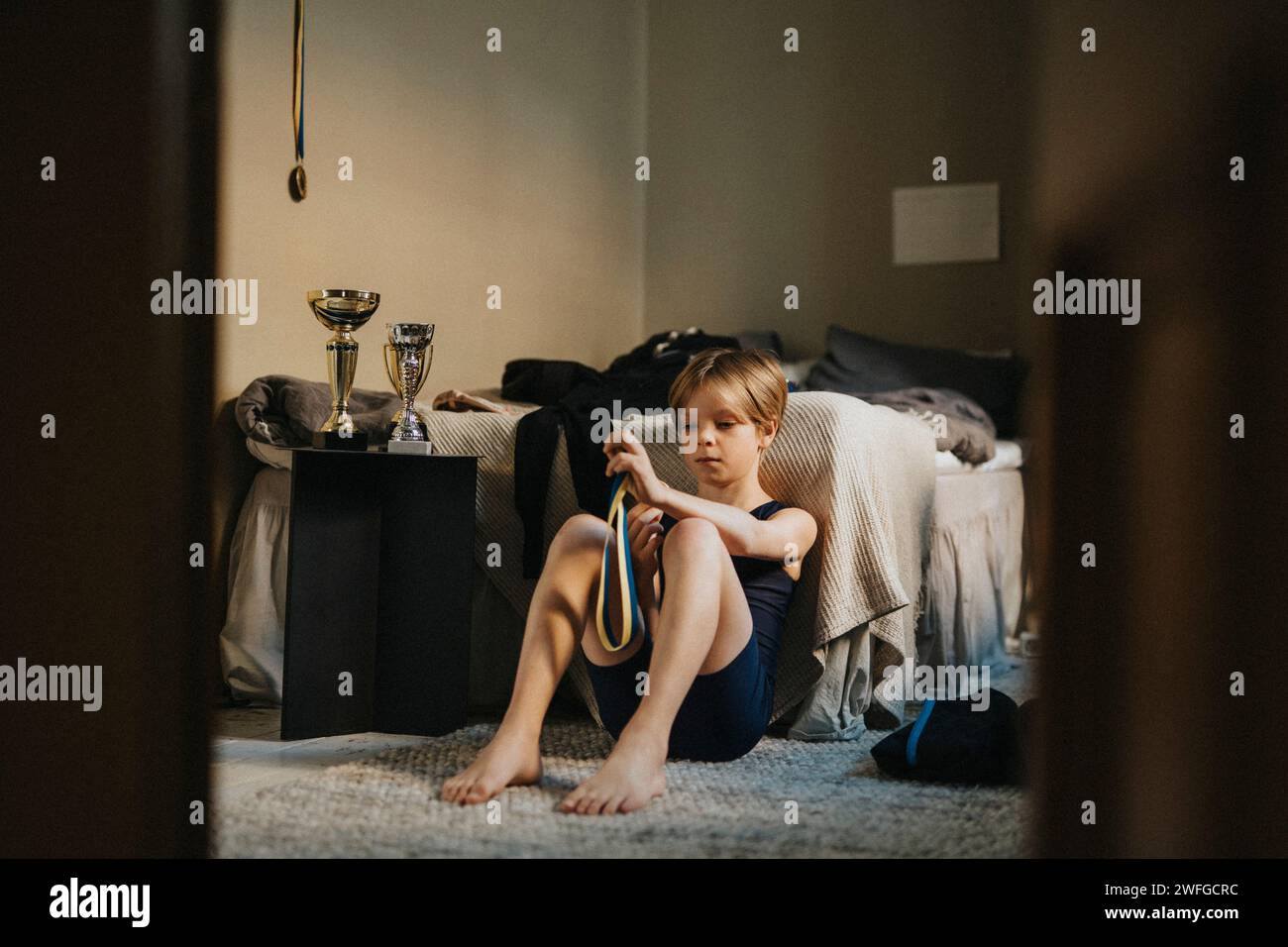 Elementary boy looking at medal while sitting in bedroom Stock Photo ...