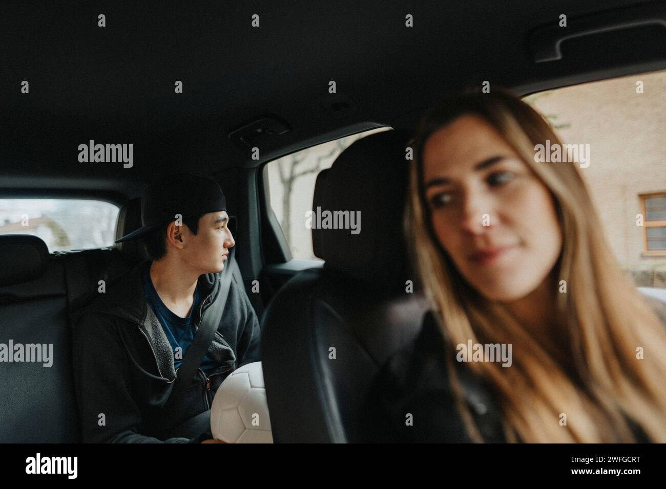 Contemplative teenage boy sitting with female coach in car Stock Photo ...