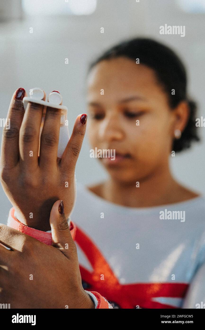 Female athlete adjusting protection band while standing in gym Stock ...
