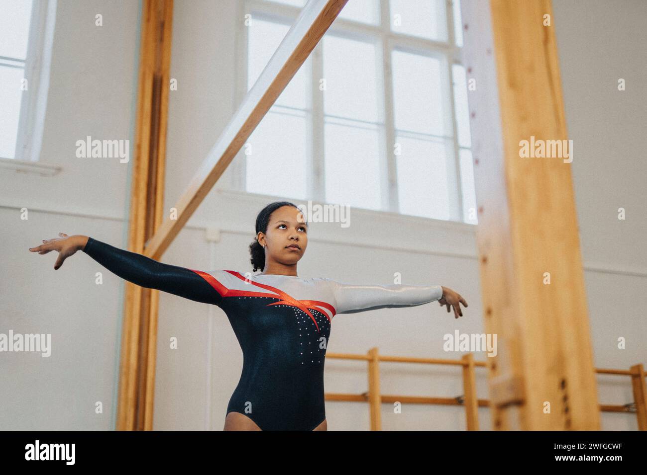 Dedicated teenage girl with arm outstretched practicing exercise in gym ...