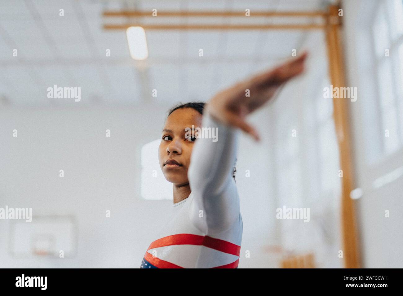 Dedicated teenage girl with arm outstretched practicing exercise in gym ...