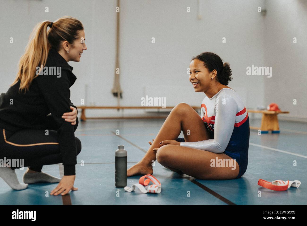 Happy teenage girl talking with female coach in school gymnasium Stock ...