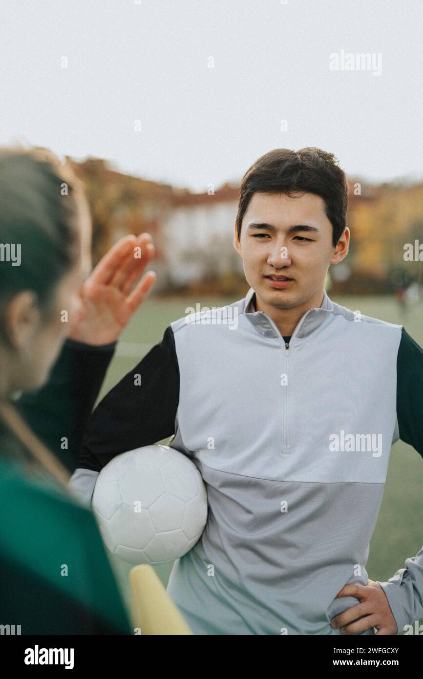 Female instructor explaining to male athlete while standing in sports ...