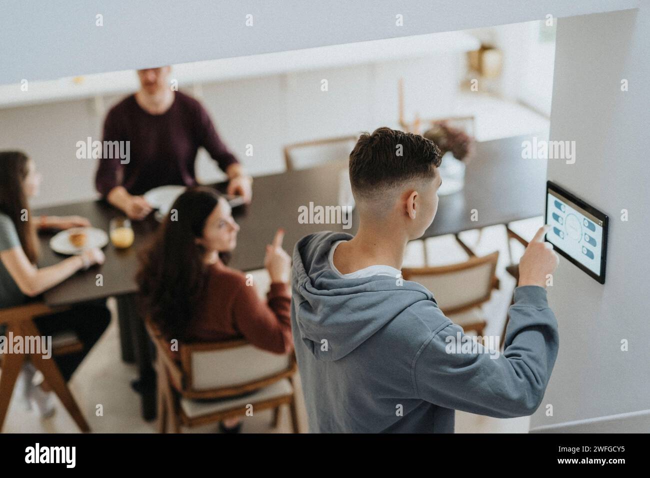 Teenage boy using home automation through digital tablet by family ...