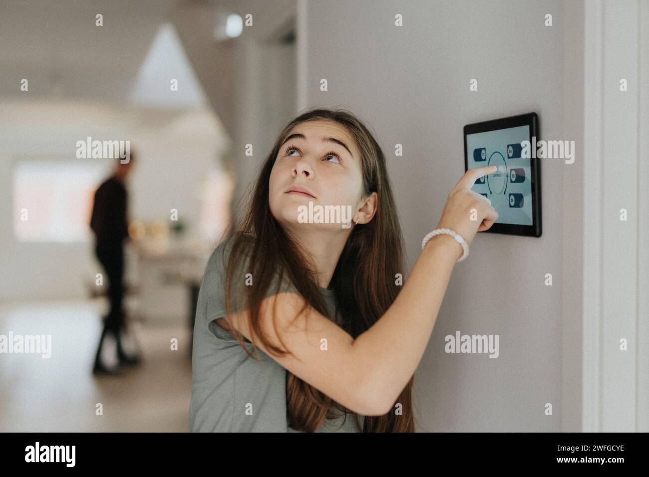 Pre-Adolescent girl adjusting room temperature through digital tablet ...