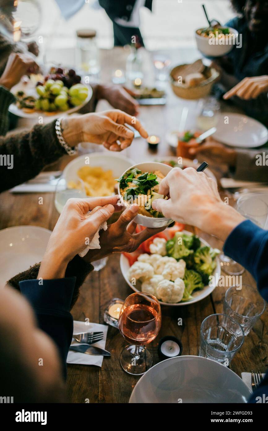 Male friends serving food at dining table during dinner party in patio ...