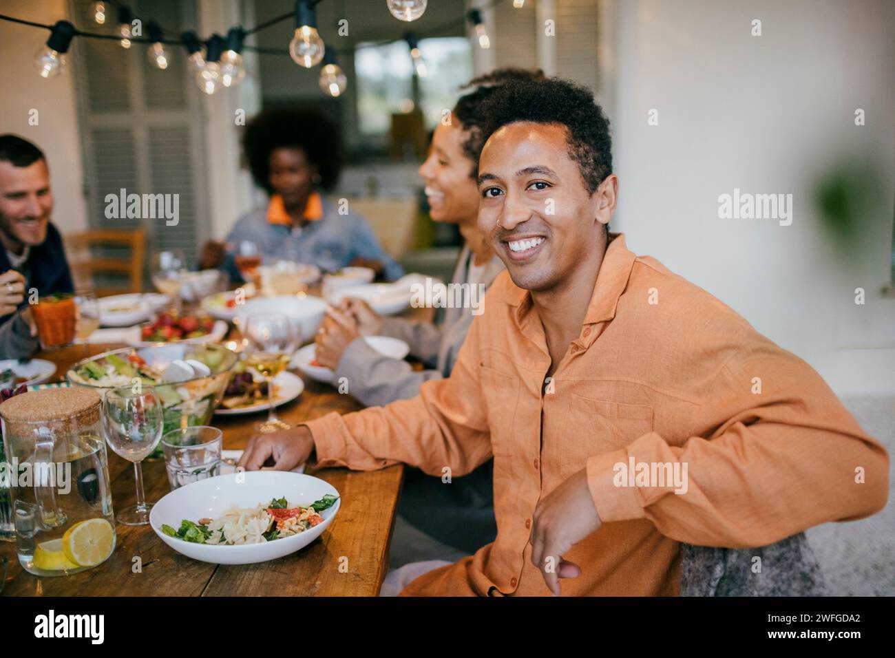 Portrait of happy man sitting at dining table during dinner party in ...