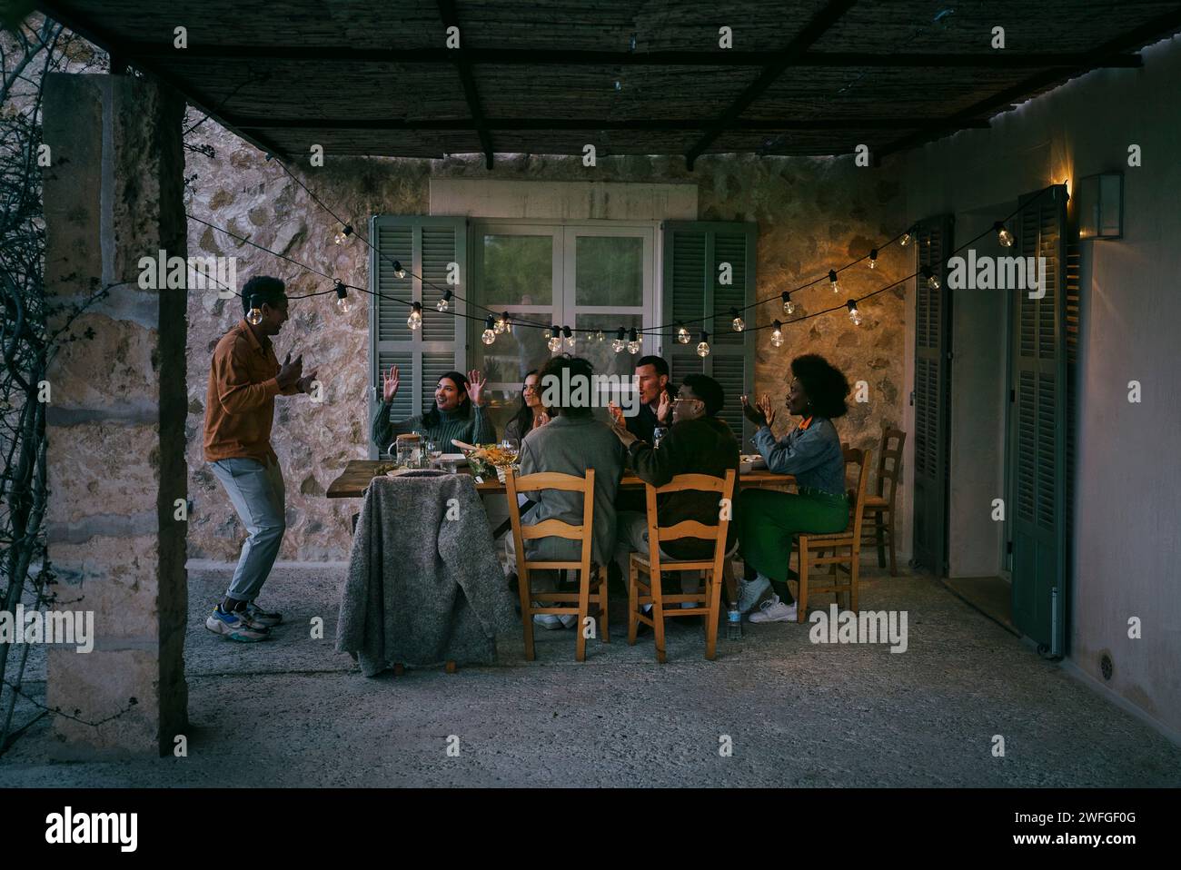 Male and female friends sitting at dining table cheering for man ...