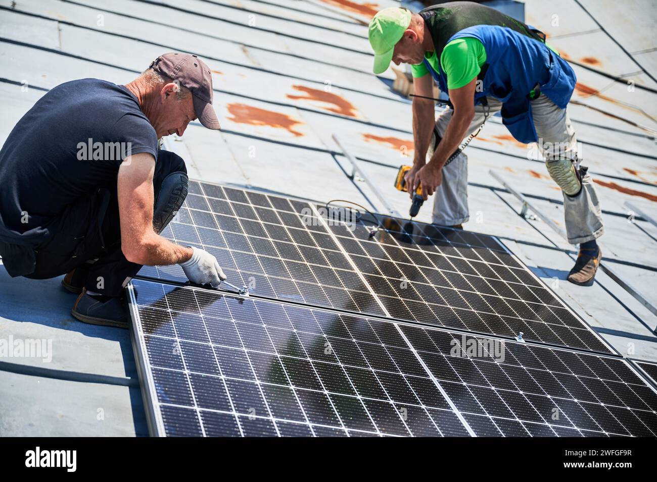Workers building photovoltaic solar panel system on rooftop of house ...