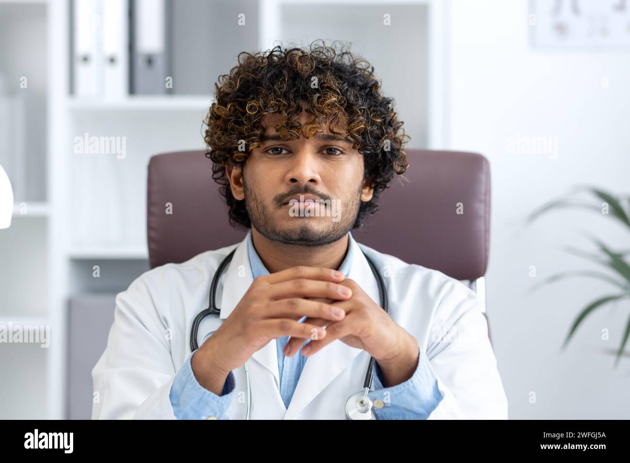 A young Hindu doctor exudes professionalism and confidence as he sits ...