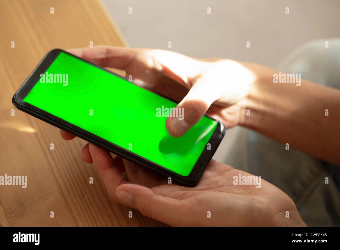 Female hands holding and clicking her smartphone with green screen close up. Online freelance ...