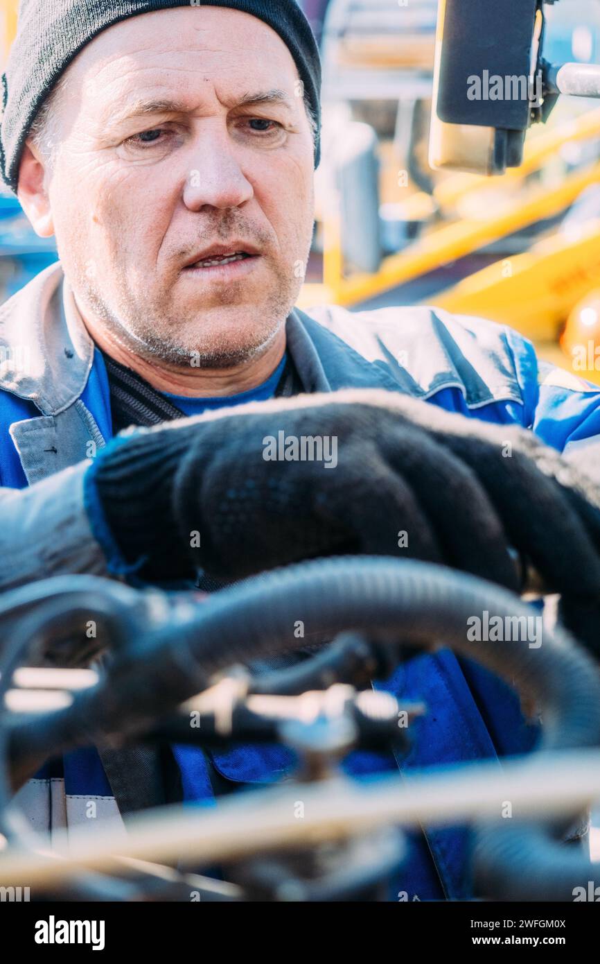 Mechanic repairs engine of tractor or heavy equipment. Farmer inspects ...