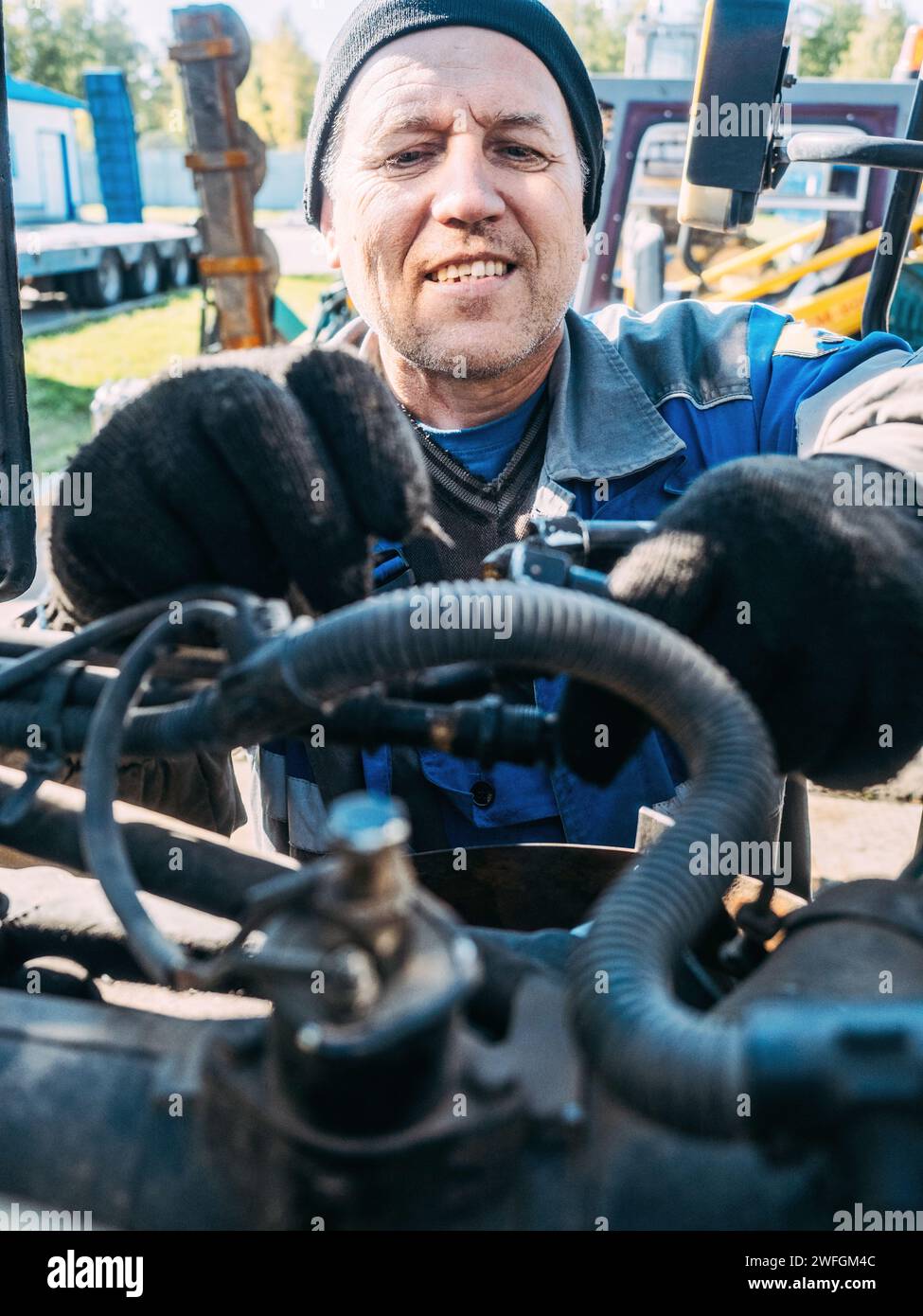 Mechanic repairs engine of tractor or heavy equipment. Farmer inspects ...